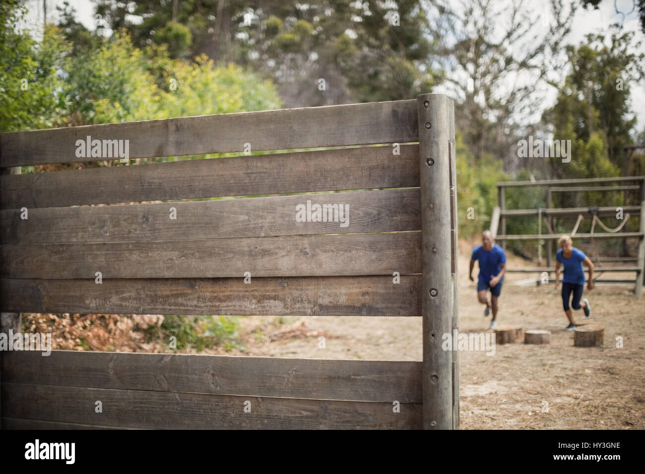 Fit man and woman running during obstacle course in boot camp Stock ...