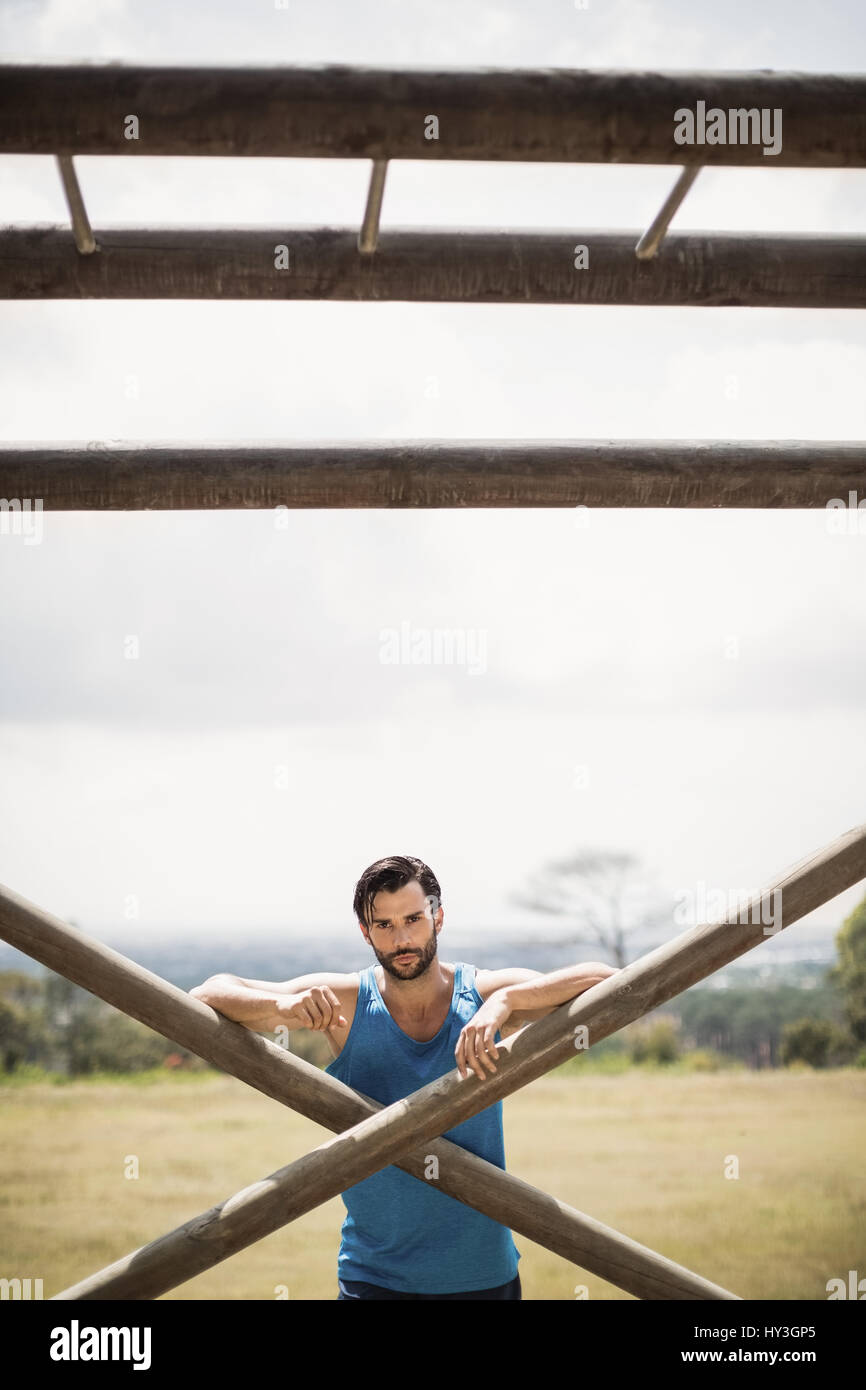 Portrait of fit man leaning on wooden bar during obstacle course in ...