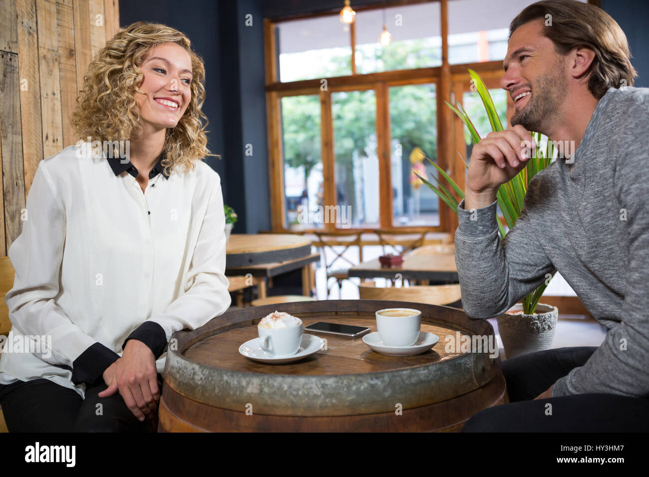 Smiling couple talking with coffee cups on table in cafe Stock Photo ...