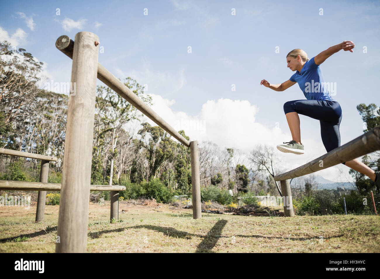 Woman jumping over the hurdles during obstacle course in boot camp ...