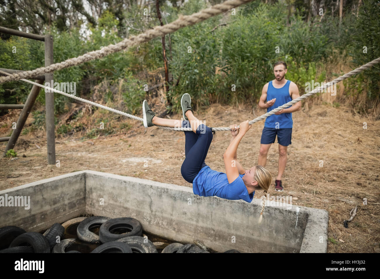 Woman climbing rope during obstacle course training at boot camp Stock ...
