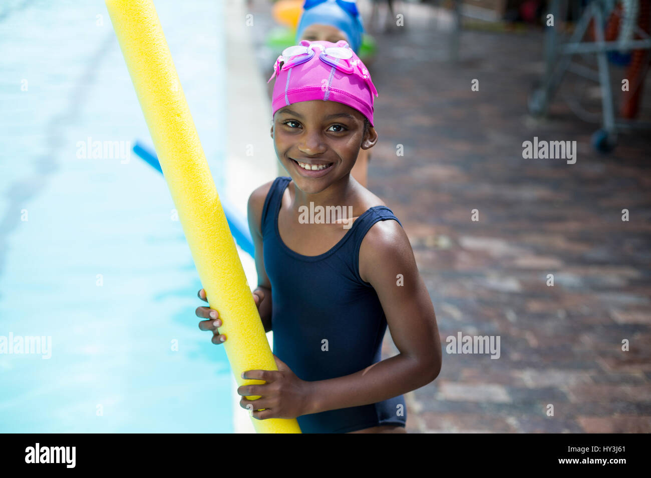 Portrait of girl holding pool noodle at poolside Stock Photo - Alamy