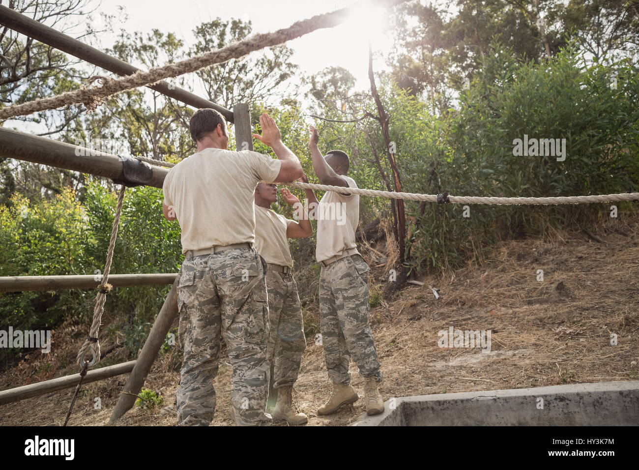 Young military soldiers giving after rope climbing during obstacle ...