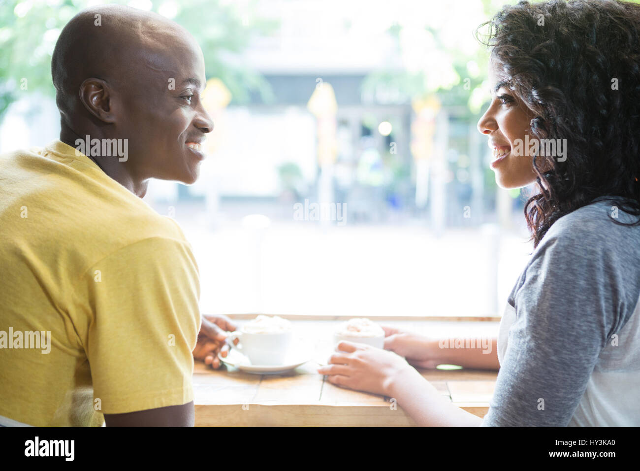 Loving young couple looking at each other at table in coffee house ...