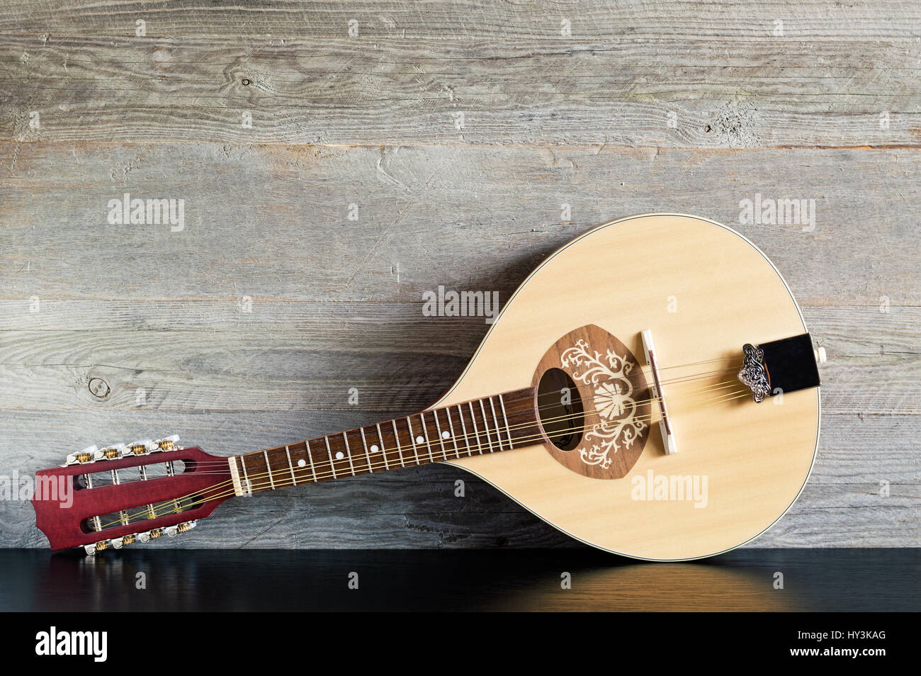 Front view of a reclined wooden flatback mandolin on a black table with ...