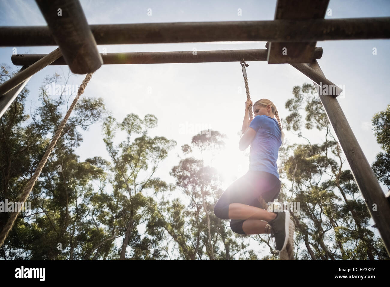 Fit woman climbing down the rope during obstacle course in boot camp ...