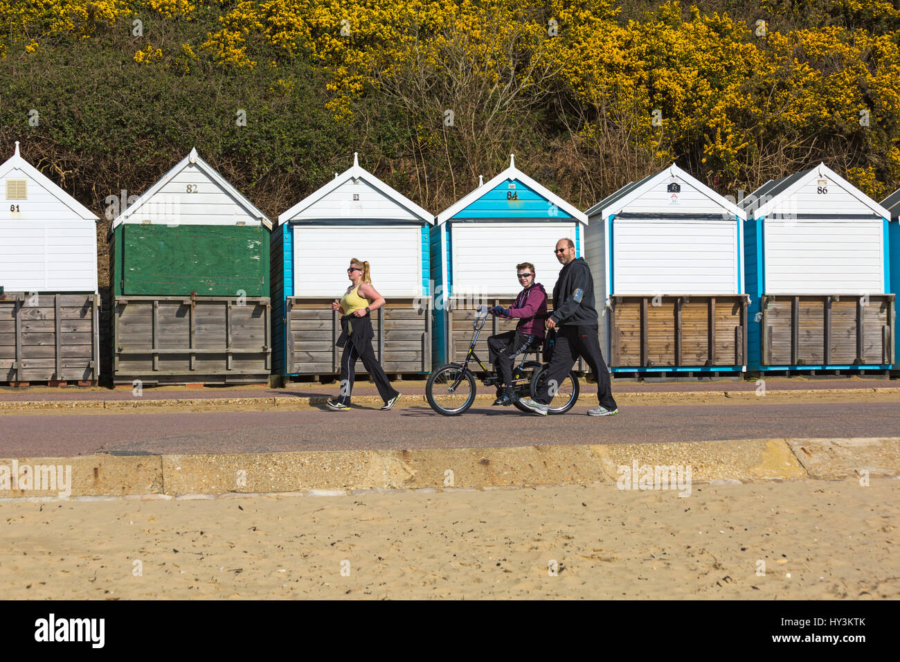 Bournemouth - visitors walking along promenade past beach huts at ...