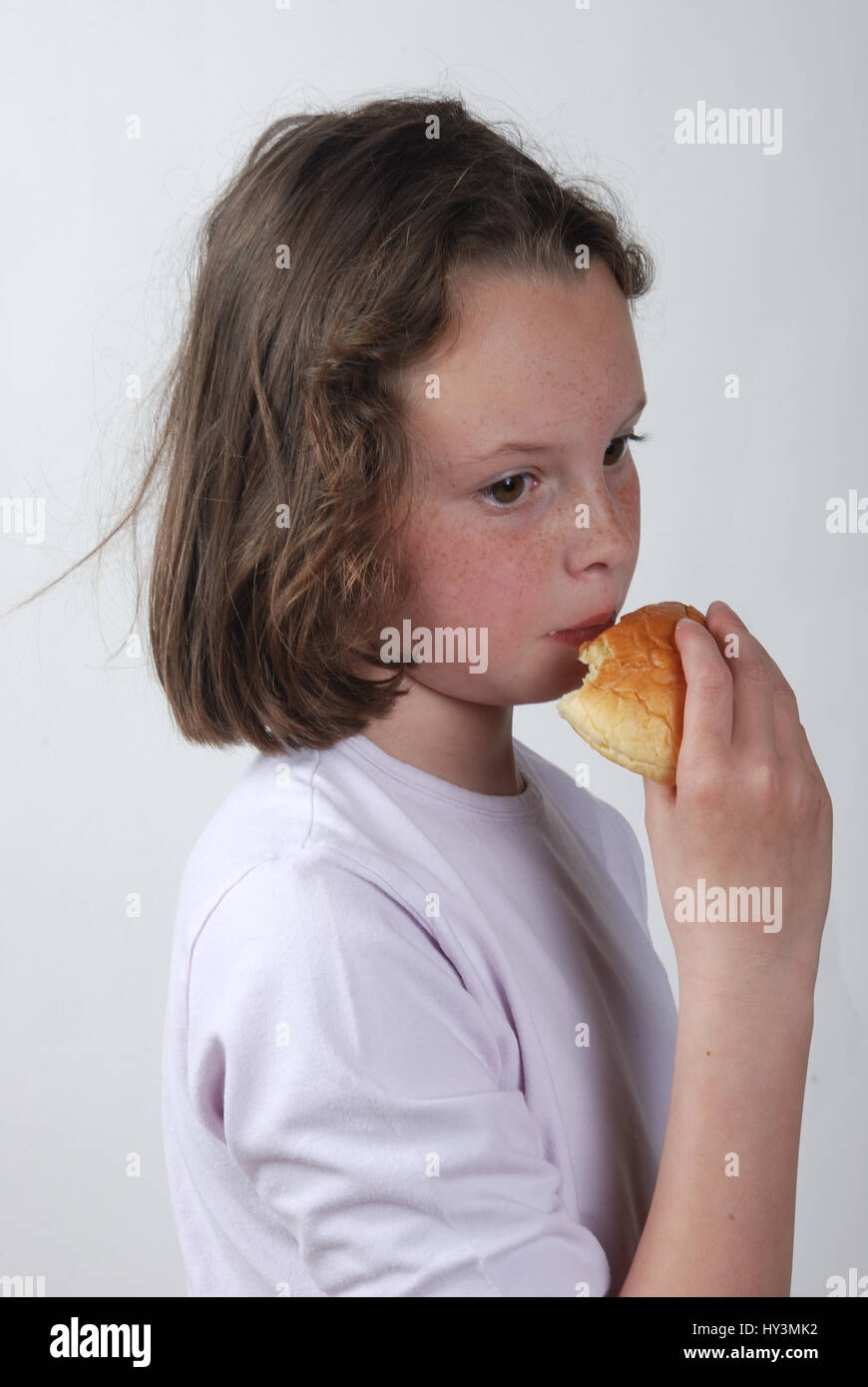 A young girl eating a bun Stock Photo - Alamy