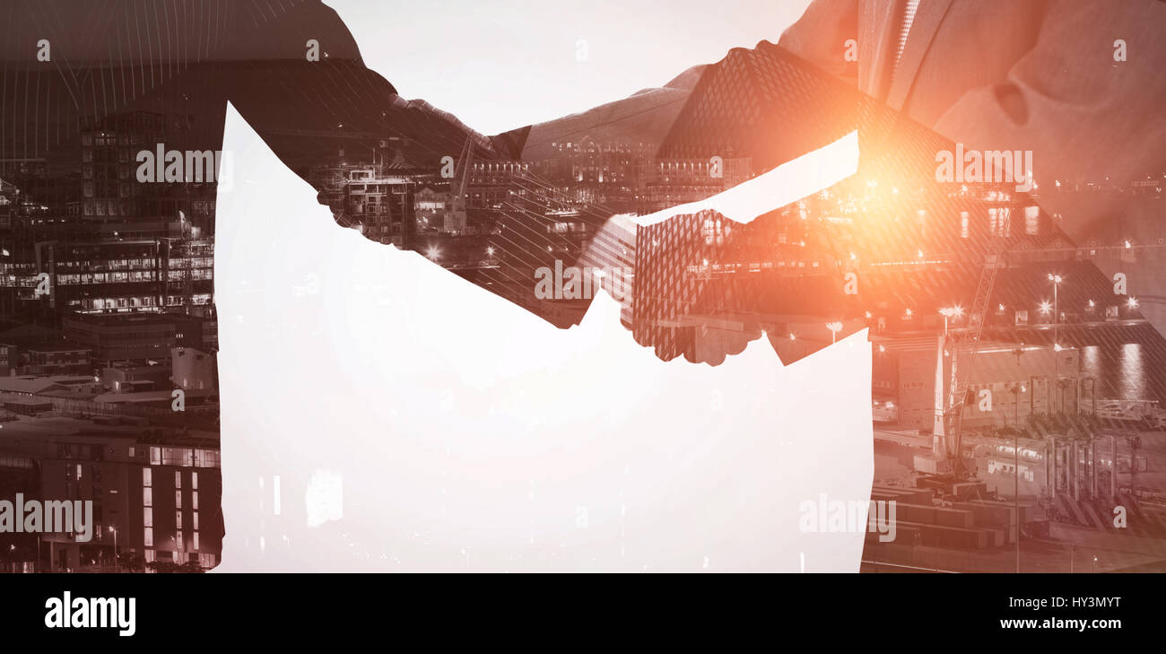 Illuminated buildings in city against composite image of handshake in ...