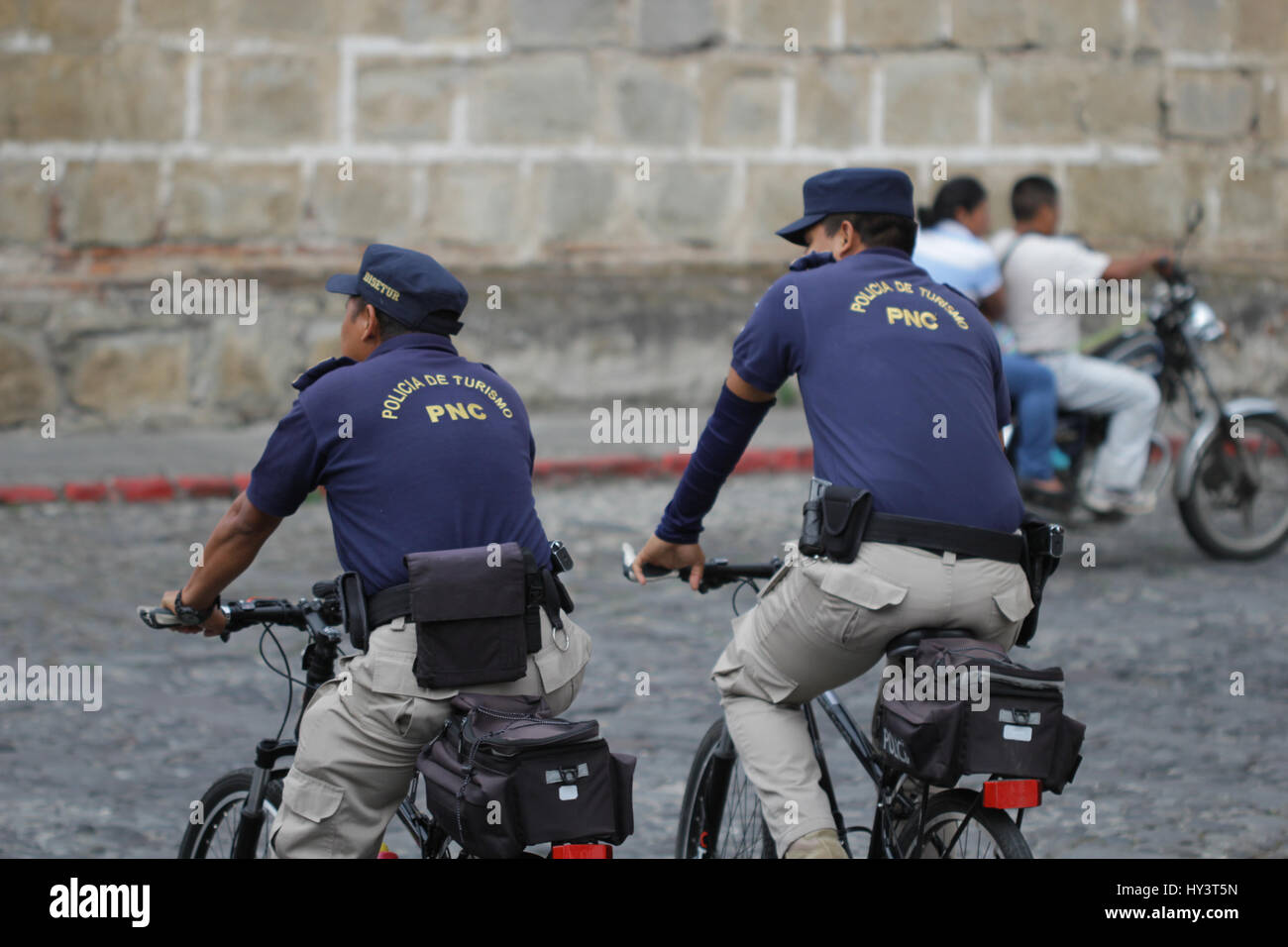 Police in blue official uniforms riding bicycles in Antigua Guatemala ...