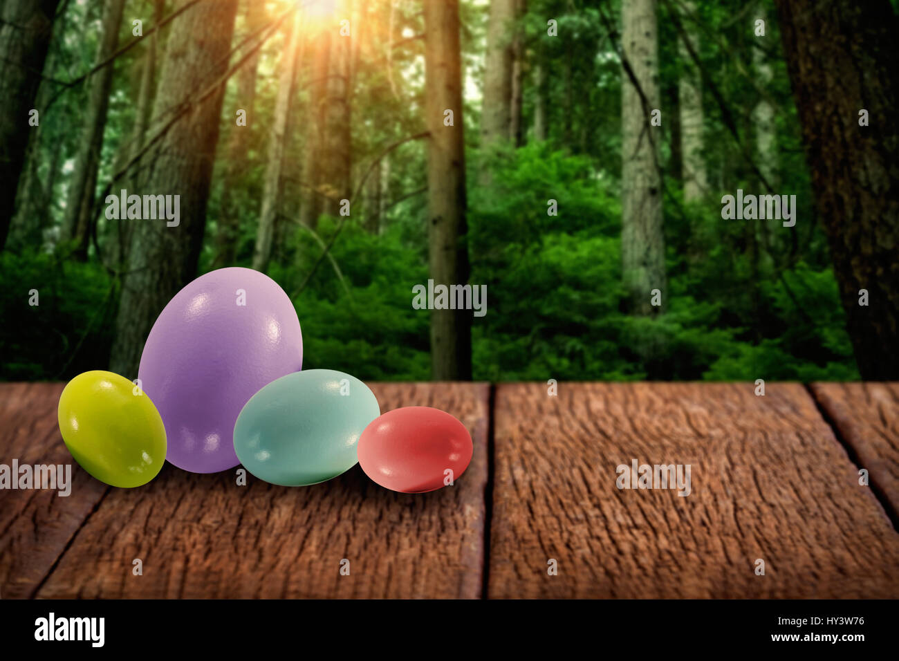Big and small multi colored Easter eggs against tall trees in forest ...