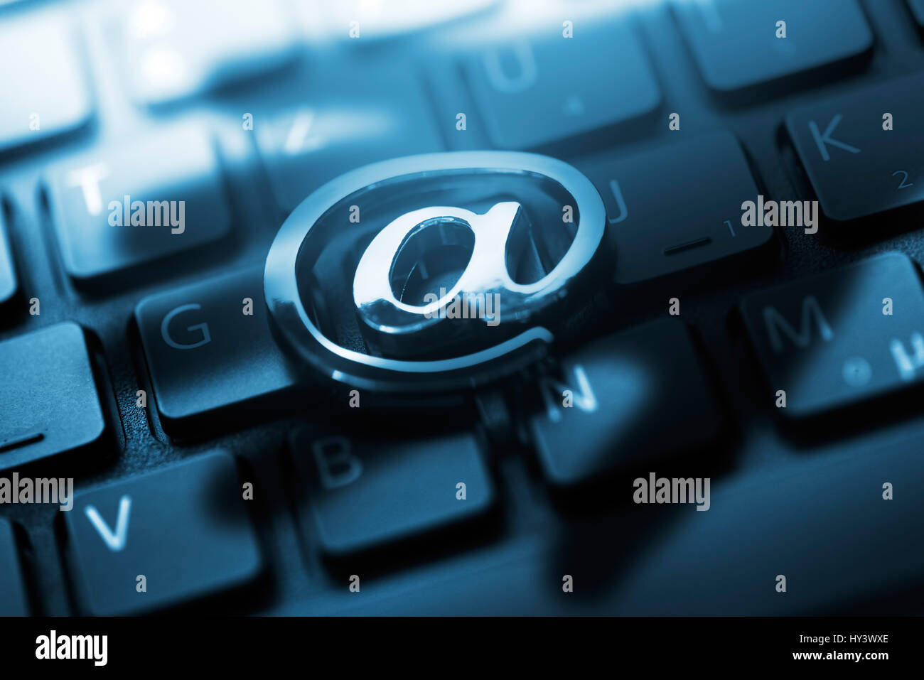 At-sign on computer keyboard with shade of a hand, symbolic photo ...