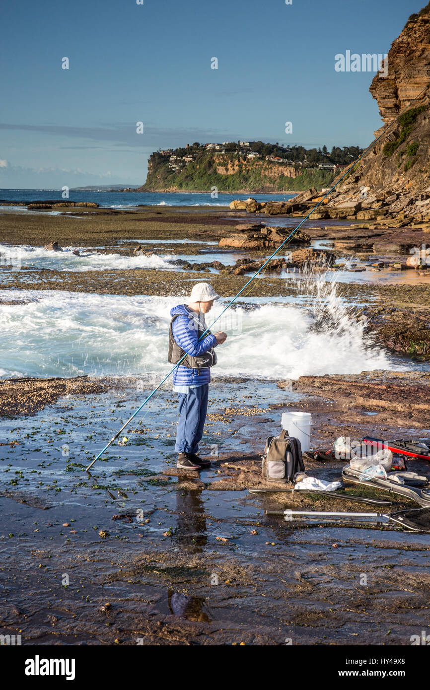 Asian man Rock fishing at Bilgola beach in Australia, wearing a life ...