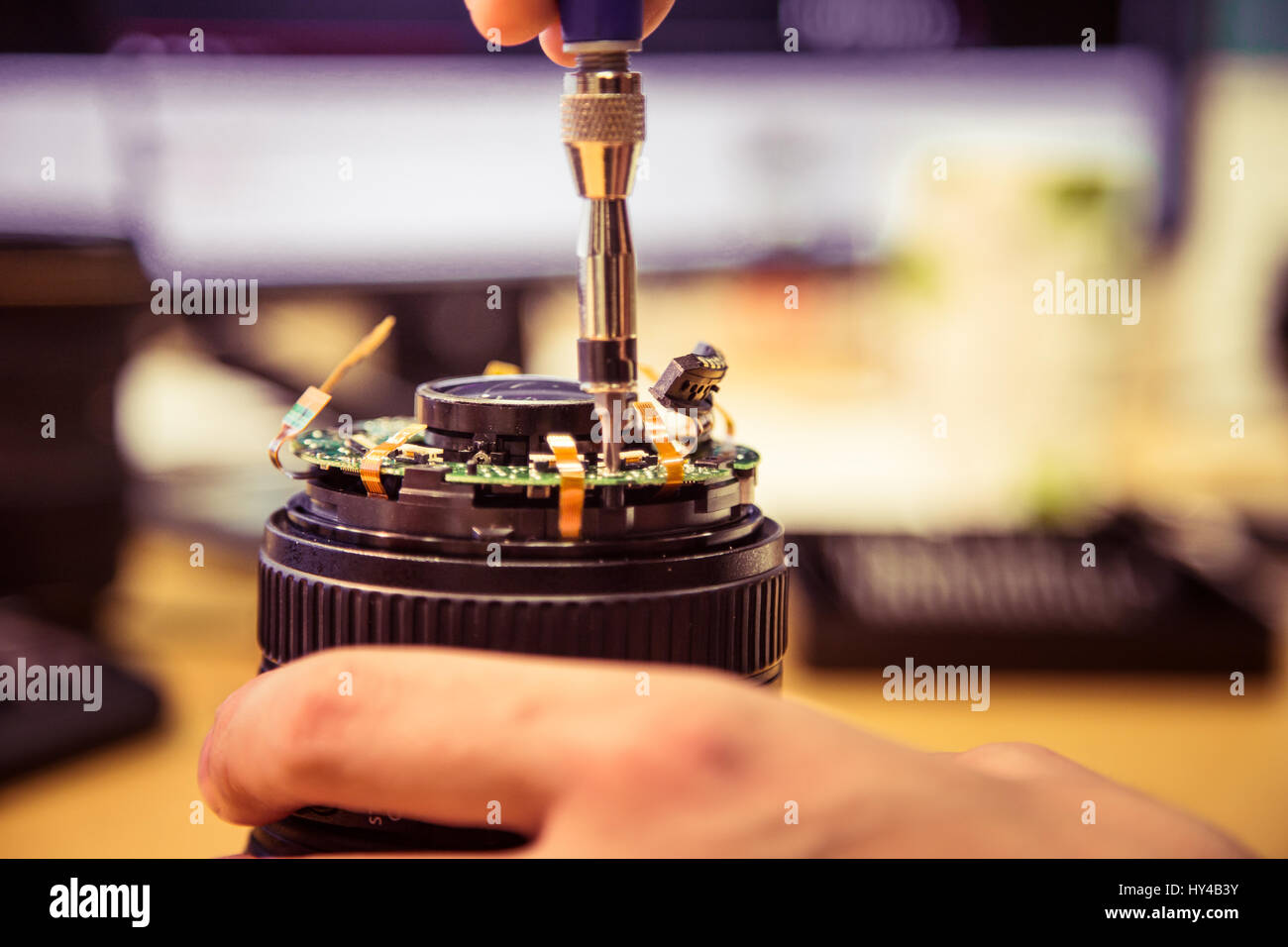 A man fixing photo camera lens on an office table Stock Photo - Alamy