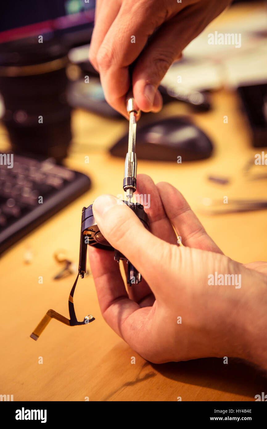 A man fixing photo camera lens on an office table Stock Photo - Alamy
