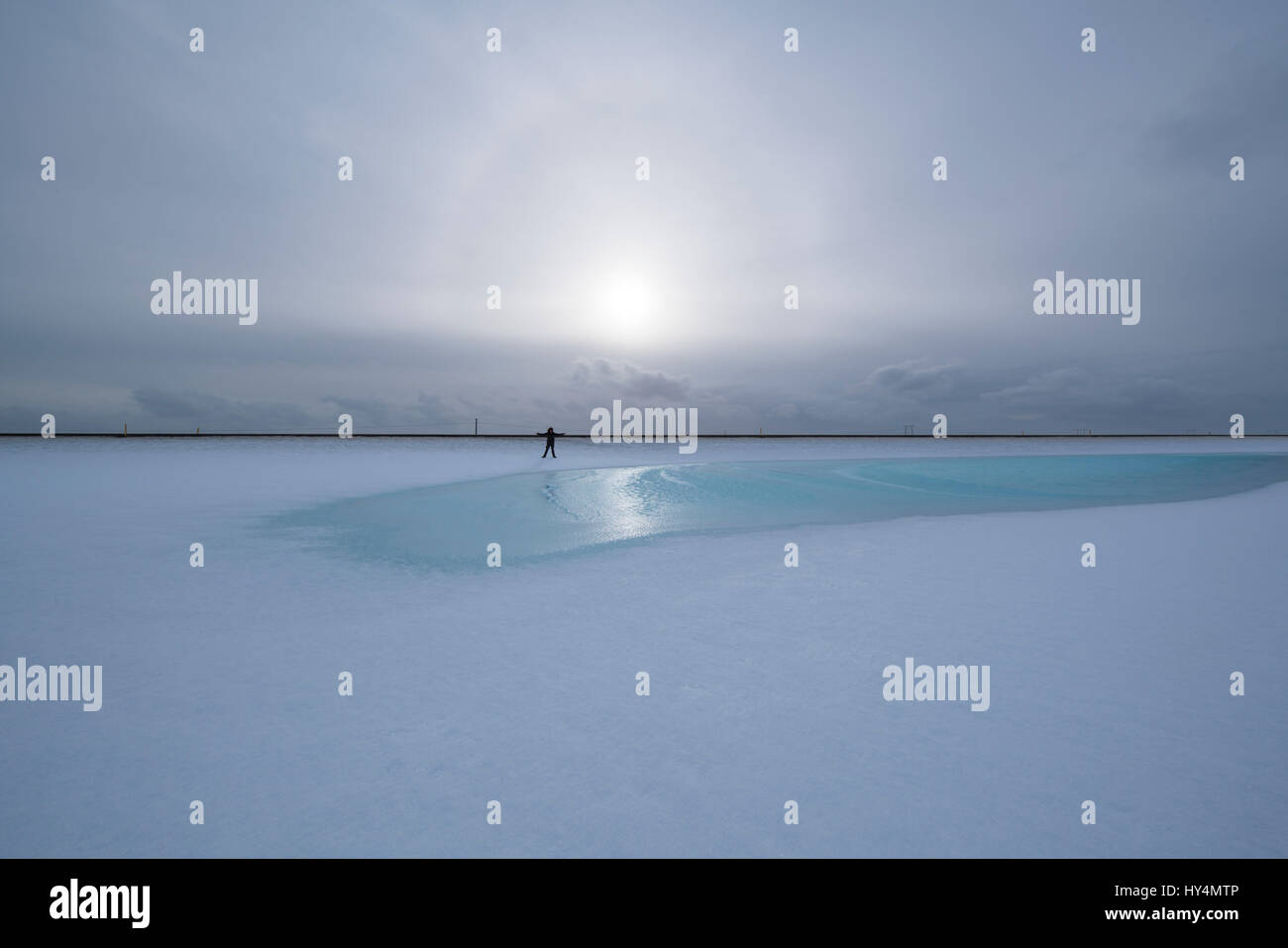 Lonely person in Icelandic lowlands with blue puddle of water and sun ...