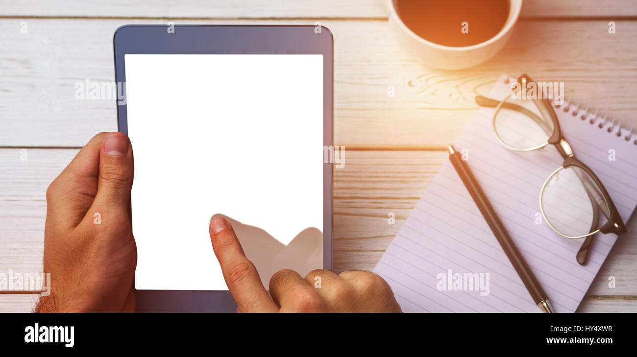 Cropped image of person using tablet at desk next to various objects ...