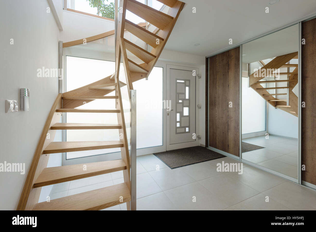 Interior of hallway with entrance door and wooden stairway Stock Photo ...