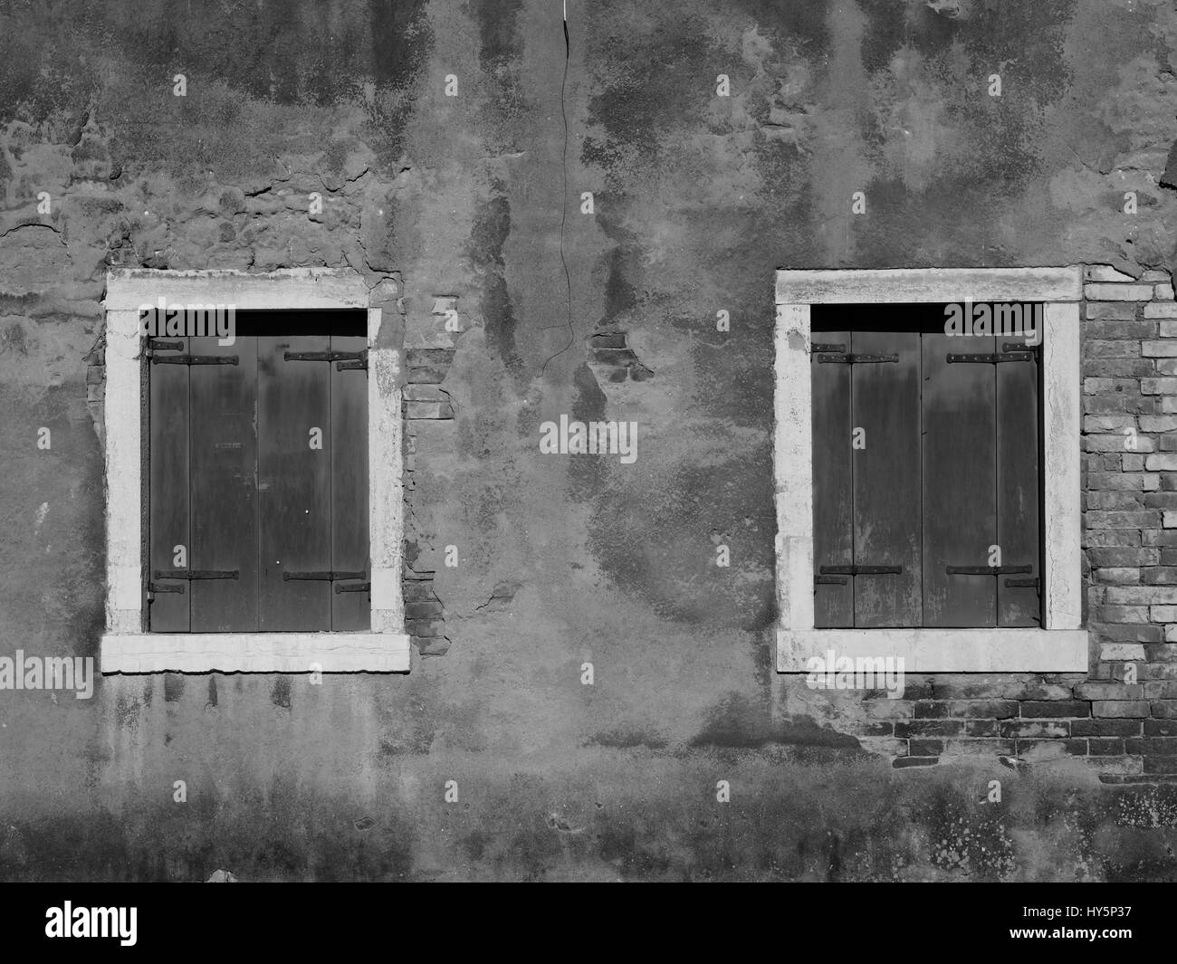 old distressed painted wall with two wooden shuttered windows and white ...