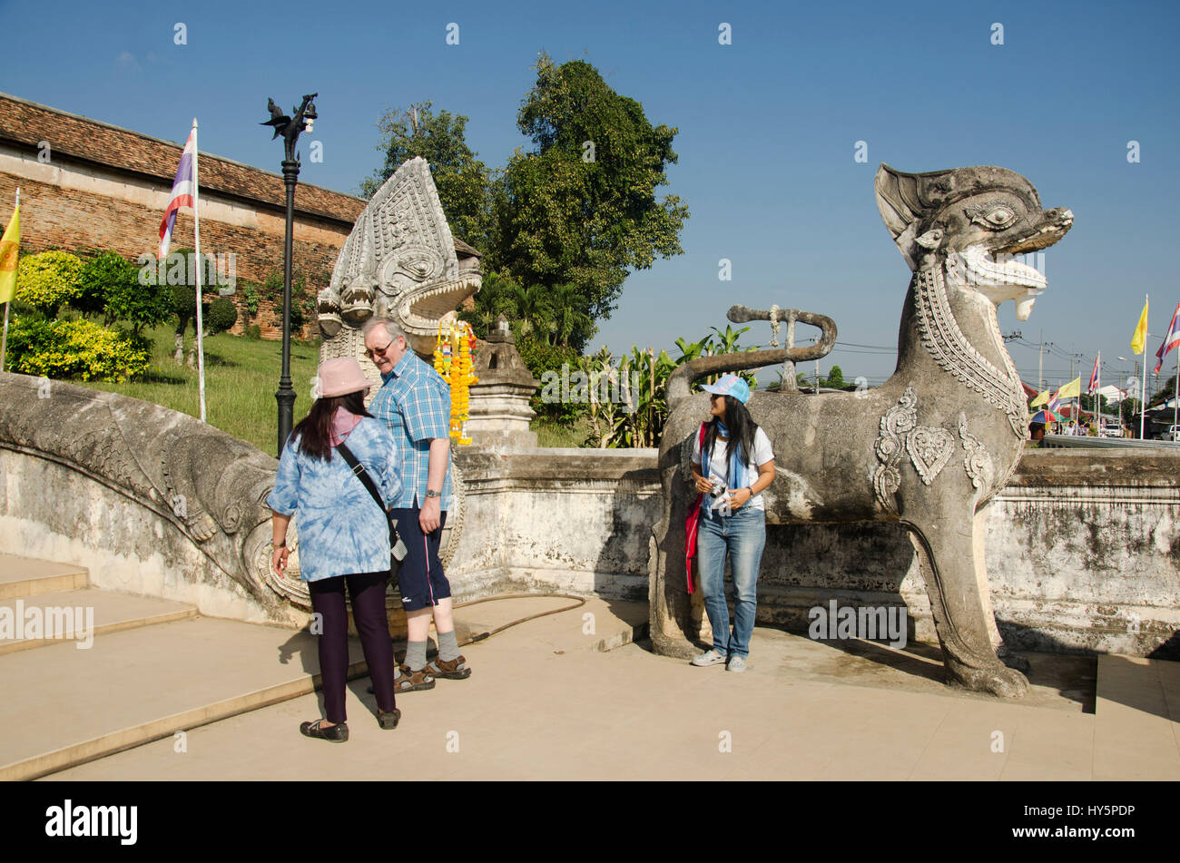 German old man and thai women posing with Singha or Lion guardian ...