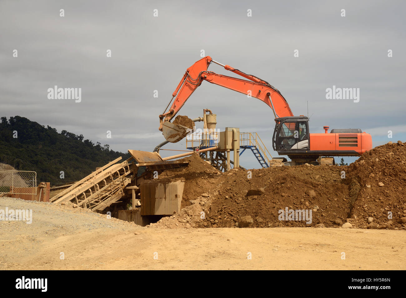 A gold miner feeds paydirt from an open cast mine into the screen that ...