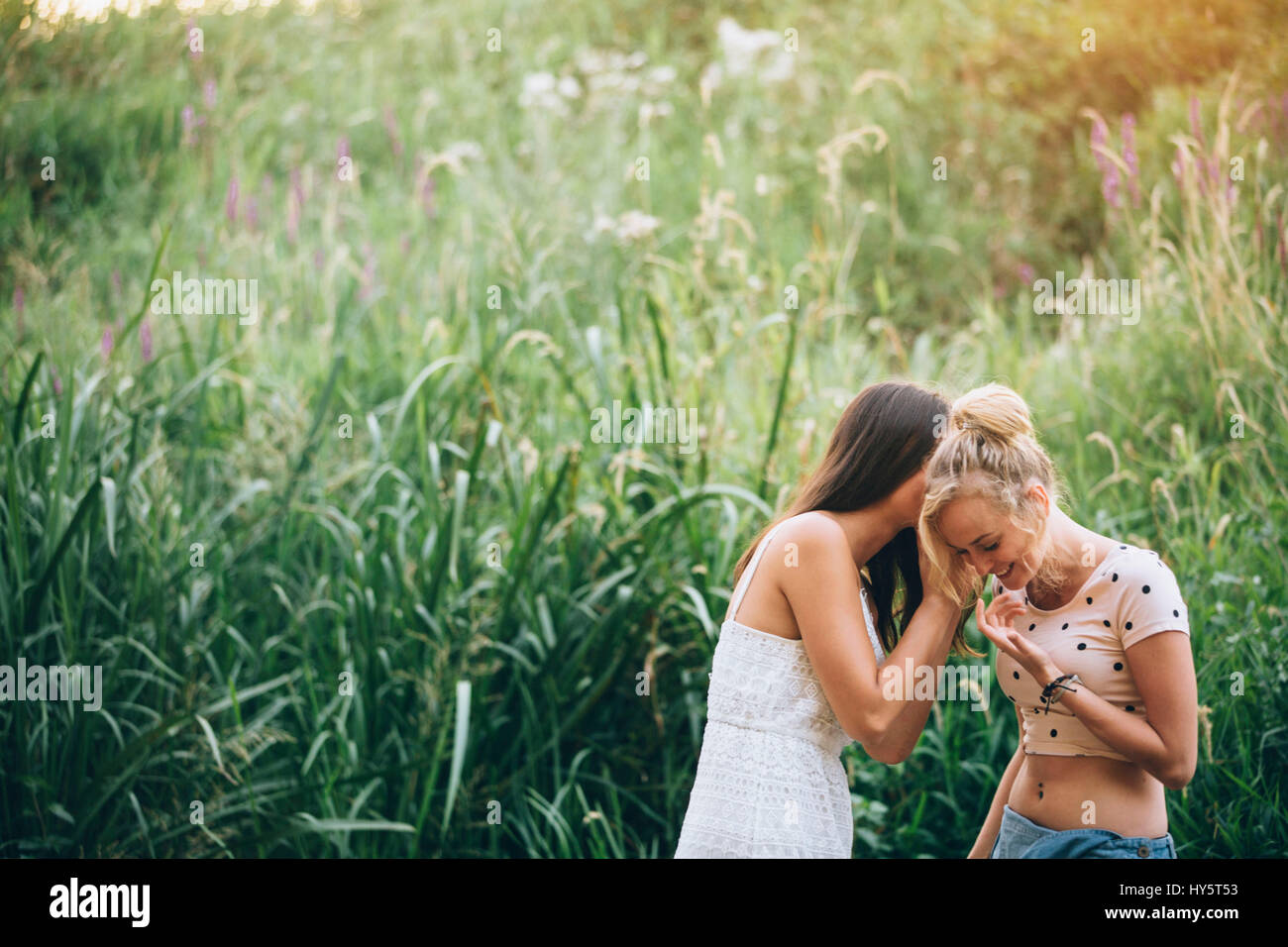 Young woman whispering something to her girlfriend Stock Photo - Alamy