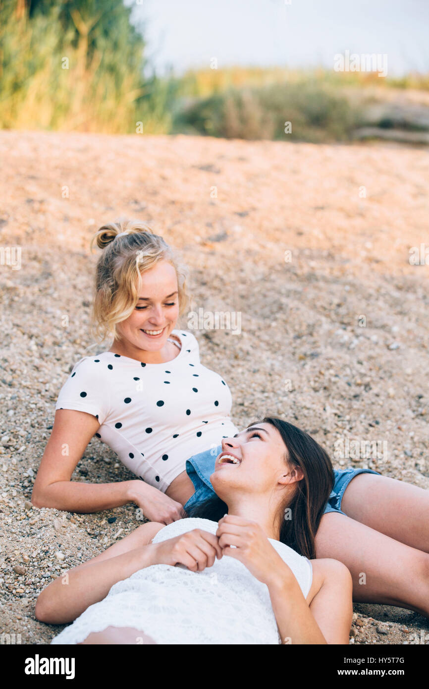 Two young women sitting on the beach and fooling around Stock Photo - Alamy
