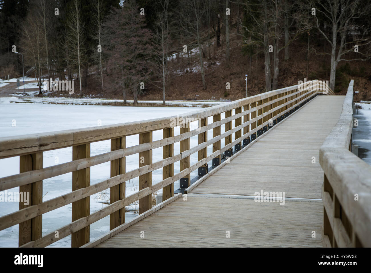 A beautiful wooden bridge over the frozen river Stock Photo - Alamy