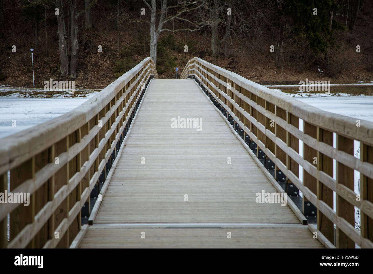 A beautiful wooden bridge over the frozen river Stock Photo - Alamy