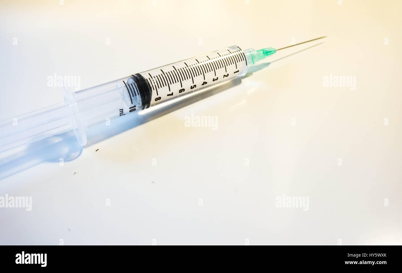 A medical syringe with a green tip is 8ml full of clear fluid against a ...