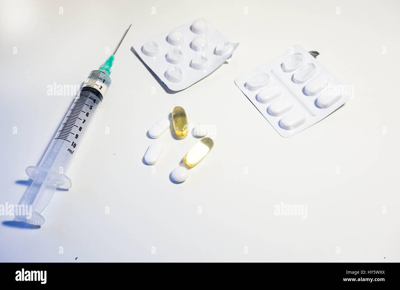 A variety of medication including a syringe with a green tip, two ...