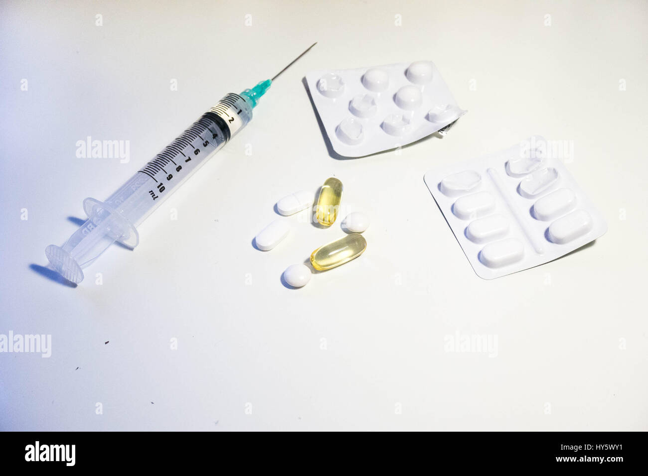 A variety of medication including a syringe with a green tip, two ...