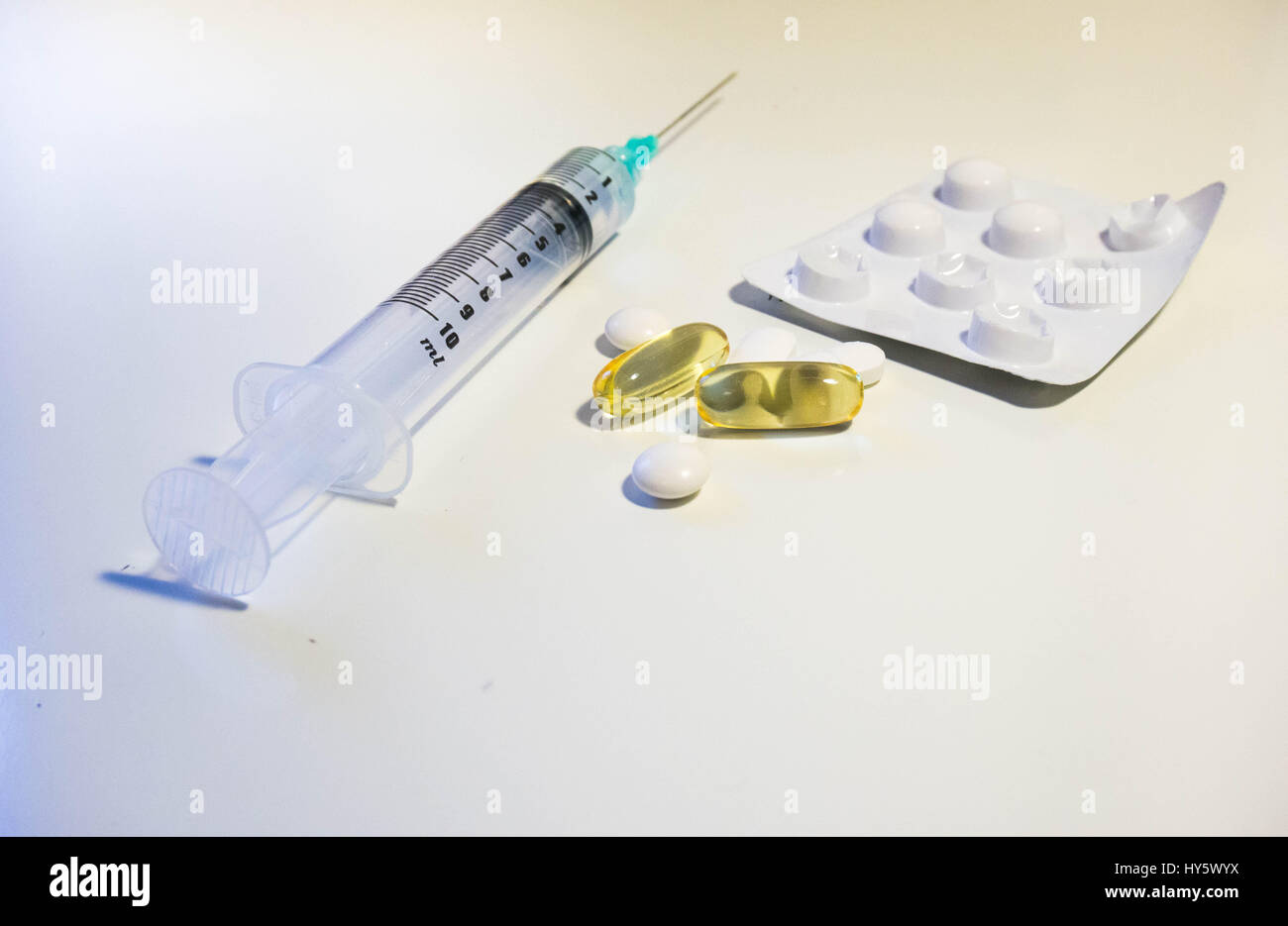 A variety of medication including a syringe with a green tip, blister ...