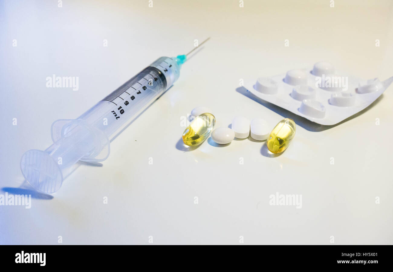 A variety of medication including a syringe with a green tip, blister ...