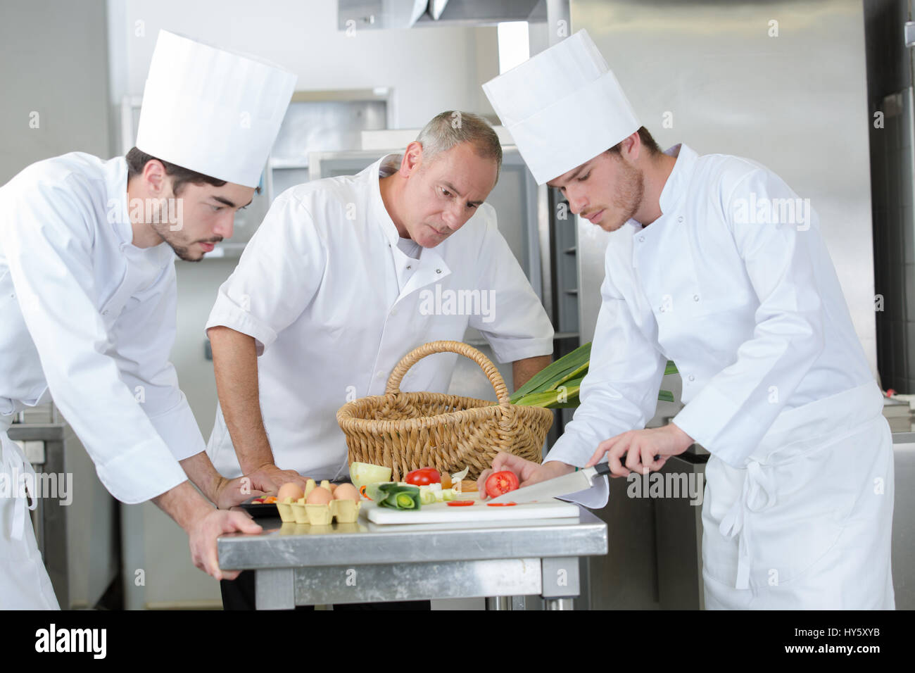 Chef watching apprentice chop vegetables Stock Photo - Alamy