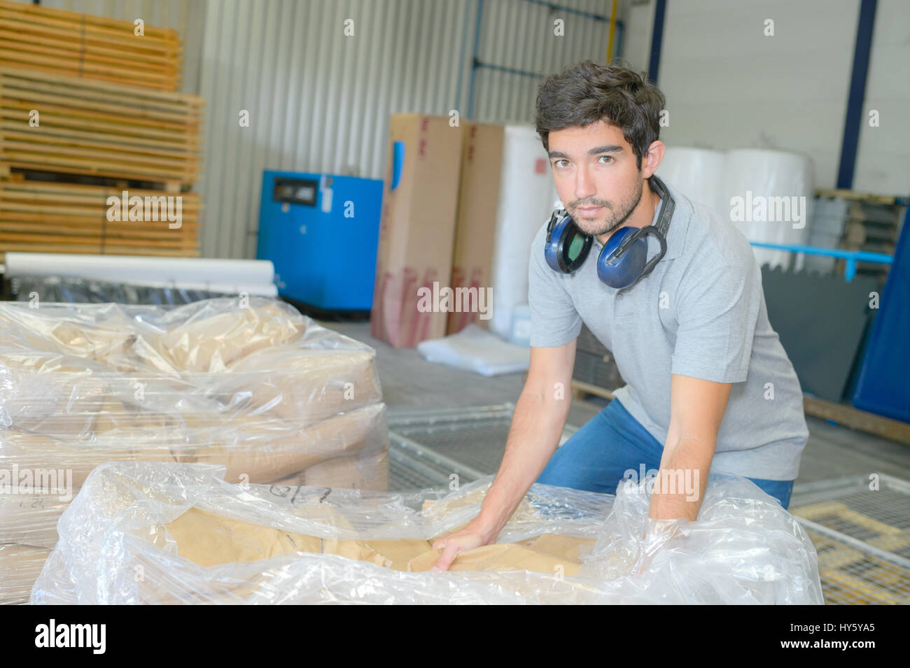 Man unwrapping plastic from pallet of bags Stock Photo - Alamy