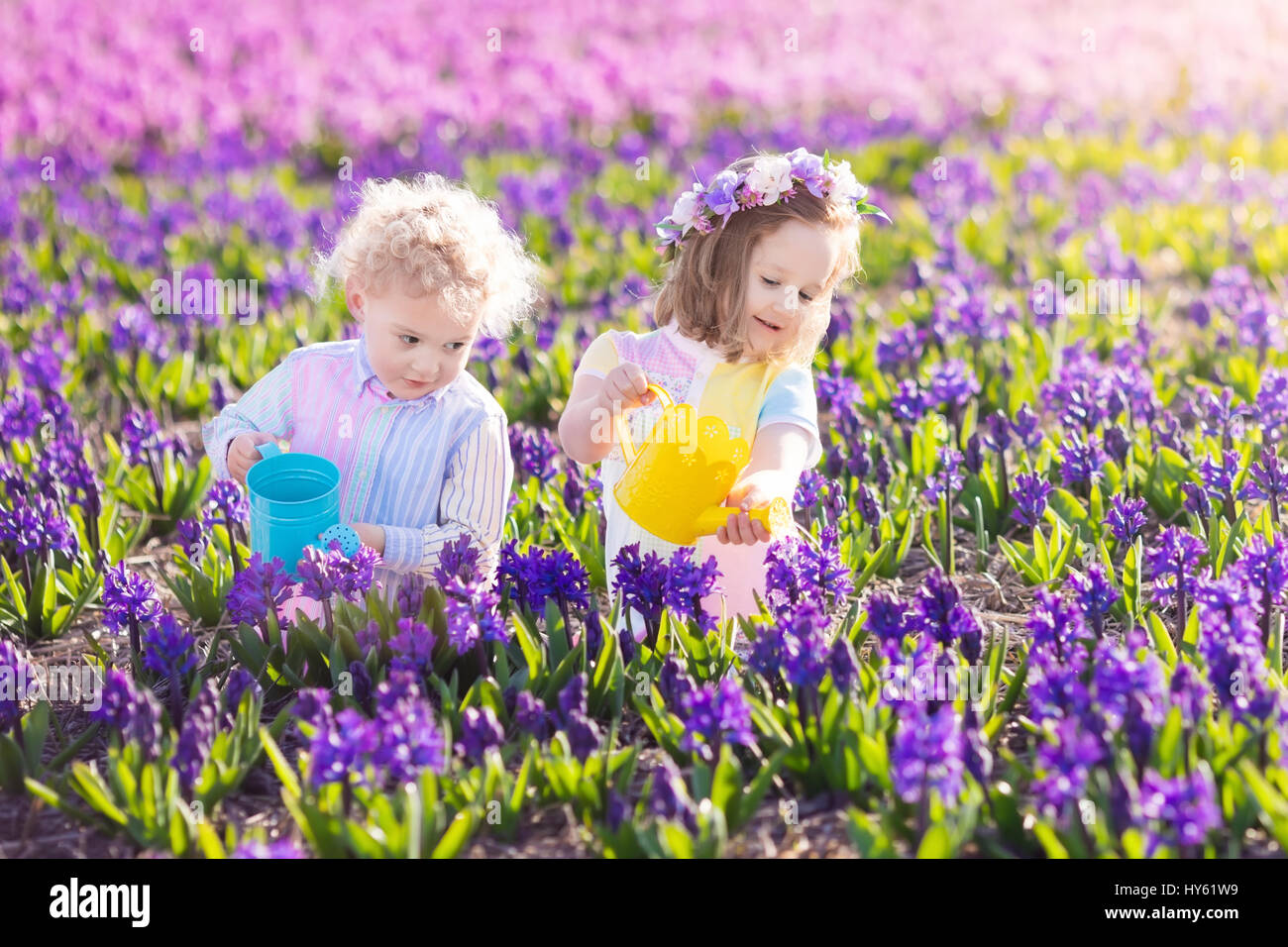Children planting spring flowers in sunny garden. Little boy and girl ...