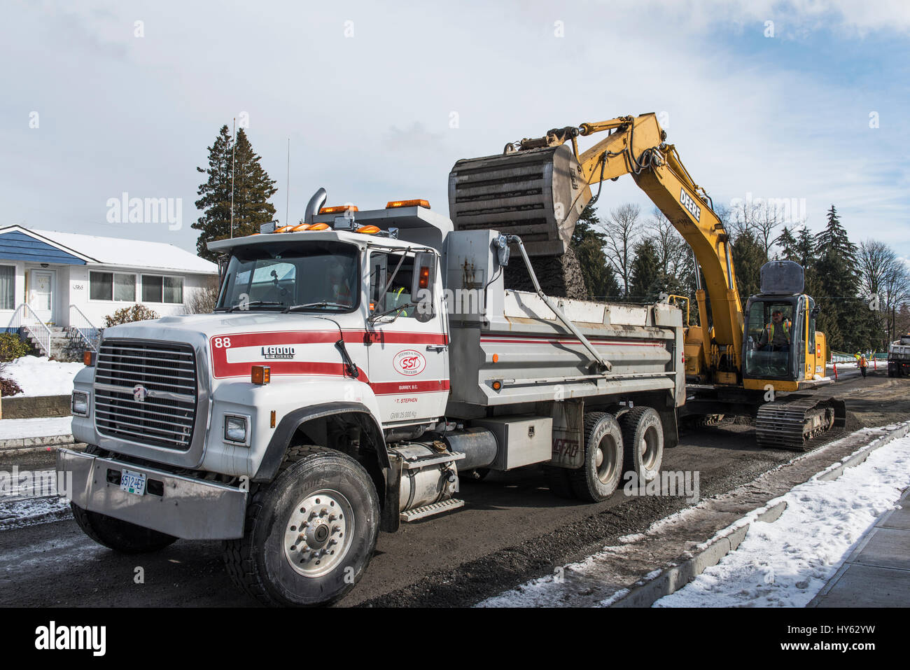 Excavator loading a dump truck during city street repairs Stock Photo ...