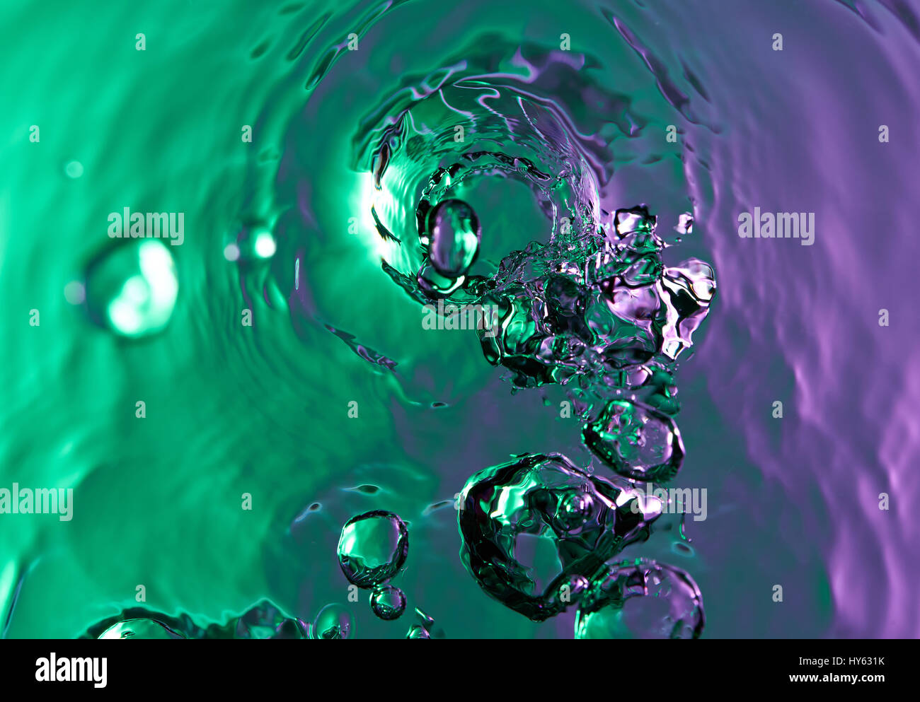 Clear water spash on green colorful liquid surface. Abstract liquid ...