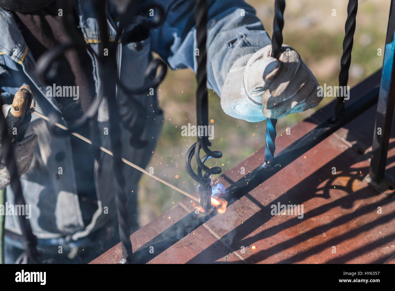 A worker welding metal handrails on the stairs. Wrought iron railings ...