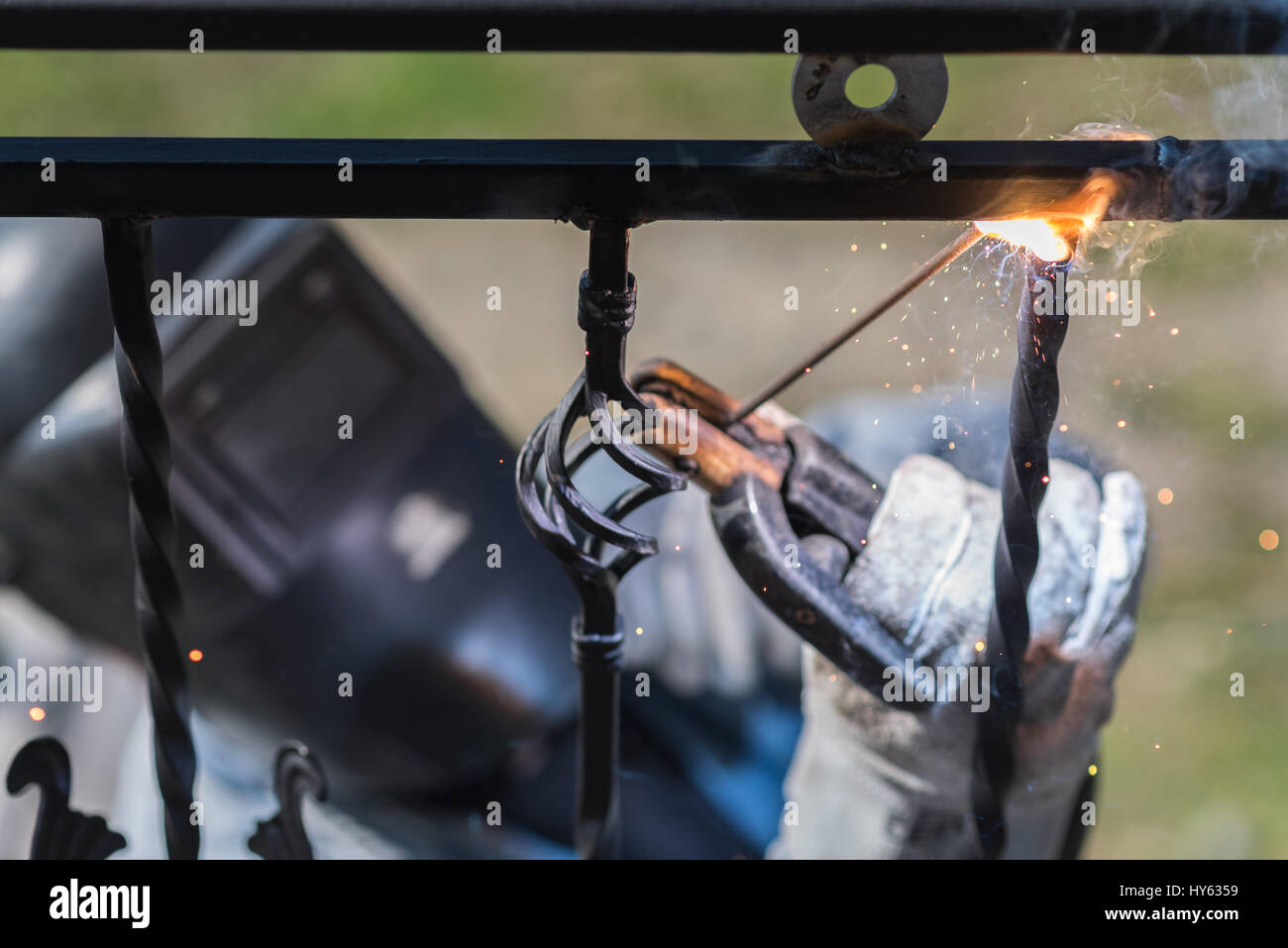 A worker welding metal handrails on the stairs. Wrought iron railings ...