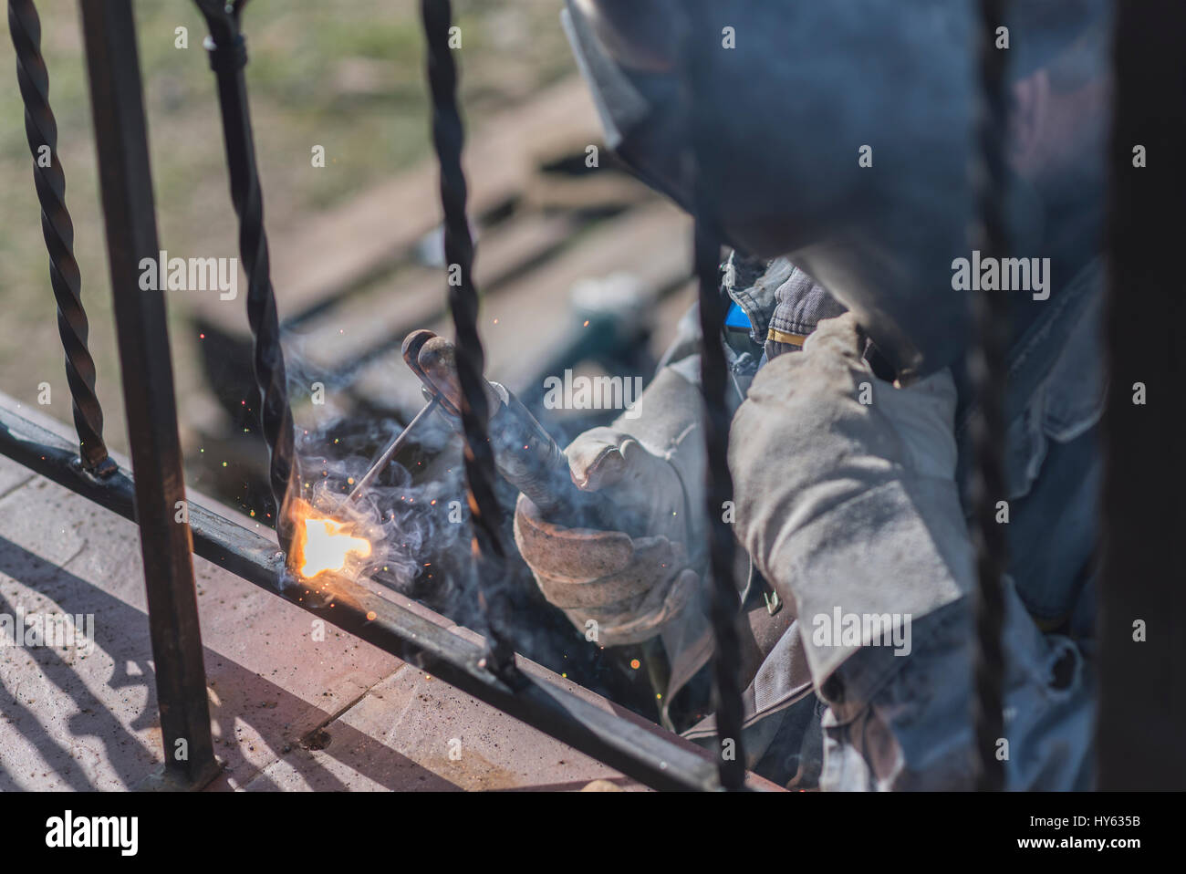 A worker welding metal handrails on the stairs. Wrought iron railings ...