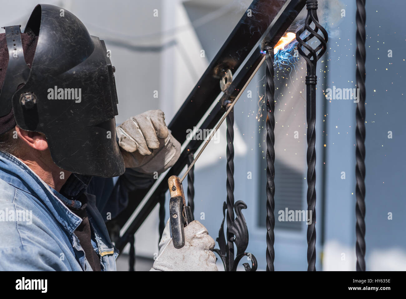 A worker welding metal handrails on the stairs. Wrought iron railings ...