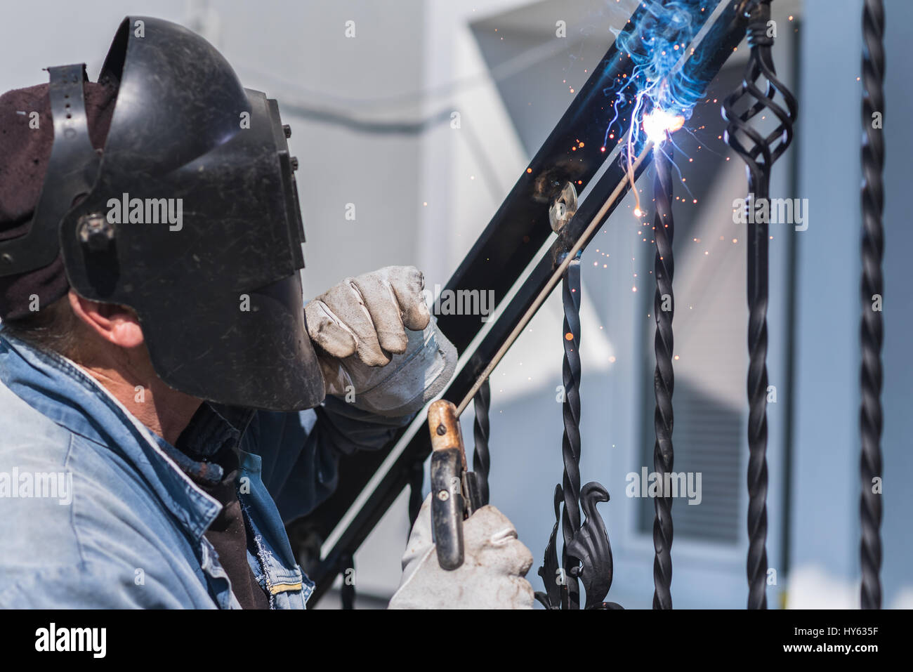 A worker welding metal handrails on the stairs. Wrought iron railings ...