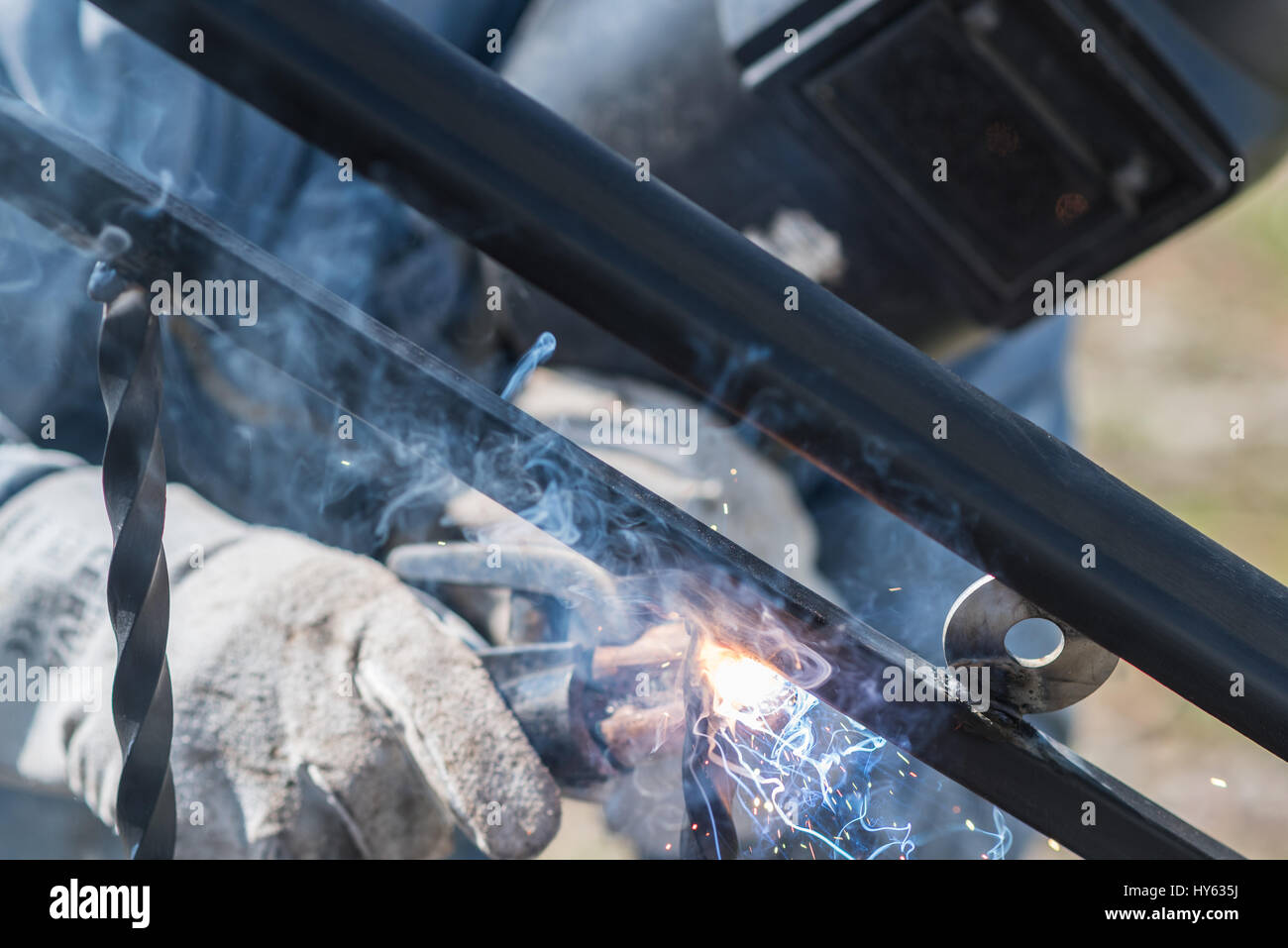 A worker welding metal handrails on the stairs. Wrought iron railings ...
