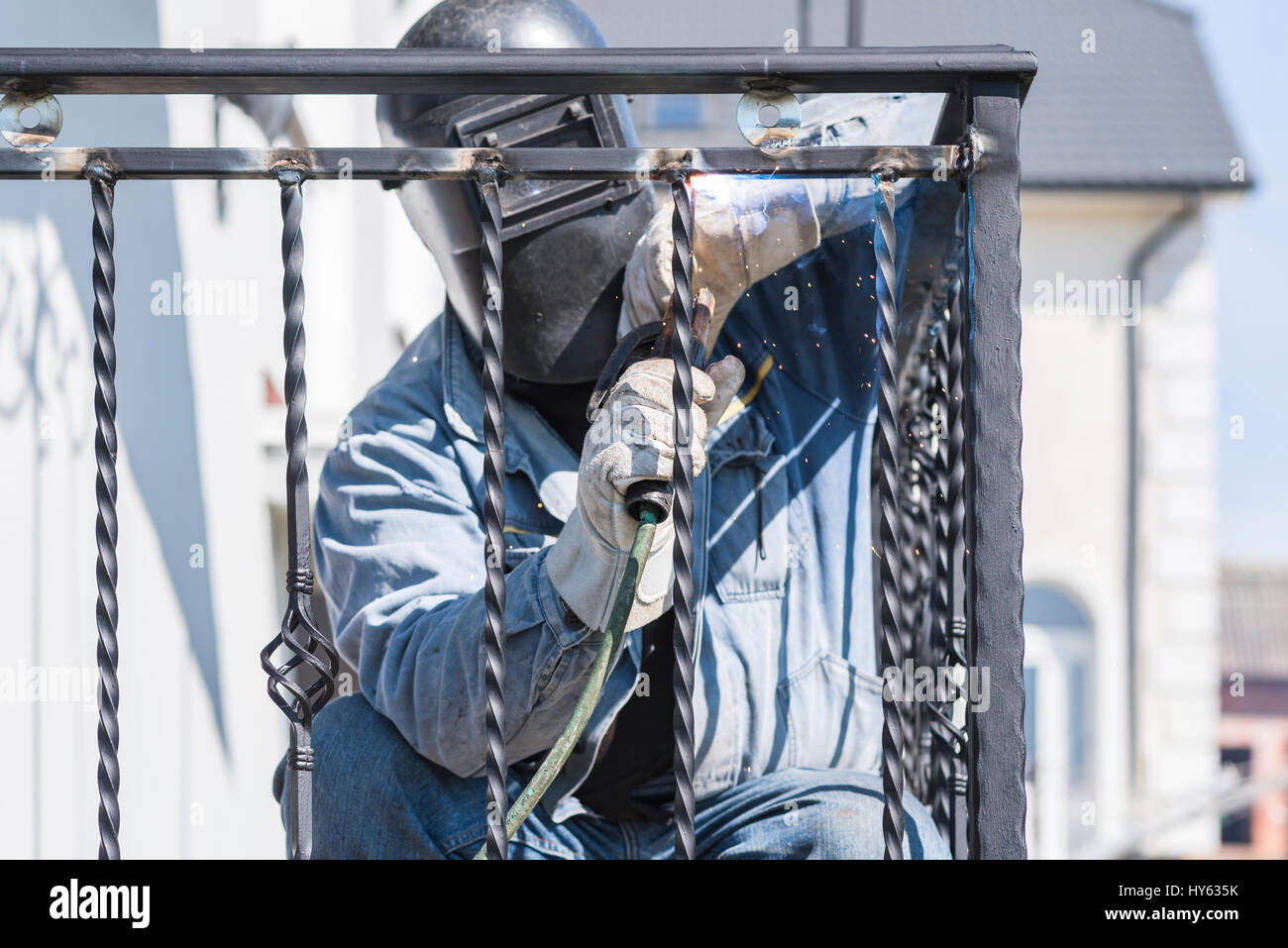 A worker welding metal handrails on the stairs. Wrought iron railings ...