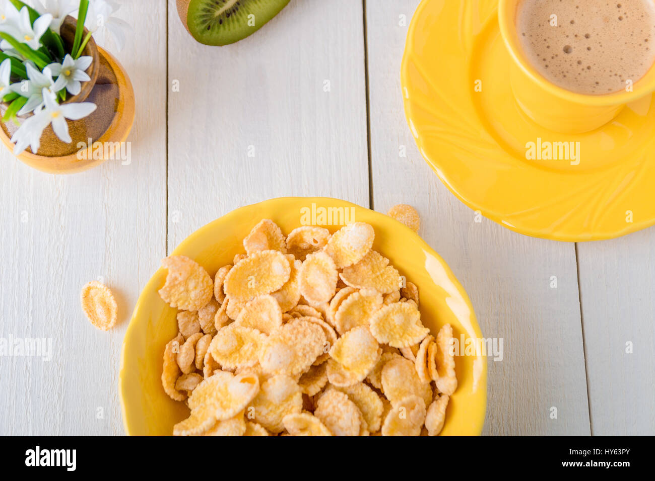 Healthy breakfast with cereal flakes near vase with flowers on white ...