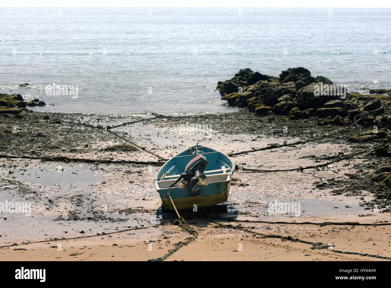 A small boat with outboard motor heavy secured to large rocks on the ...