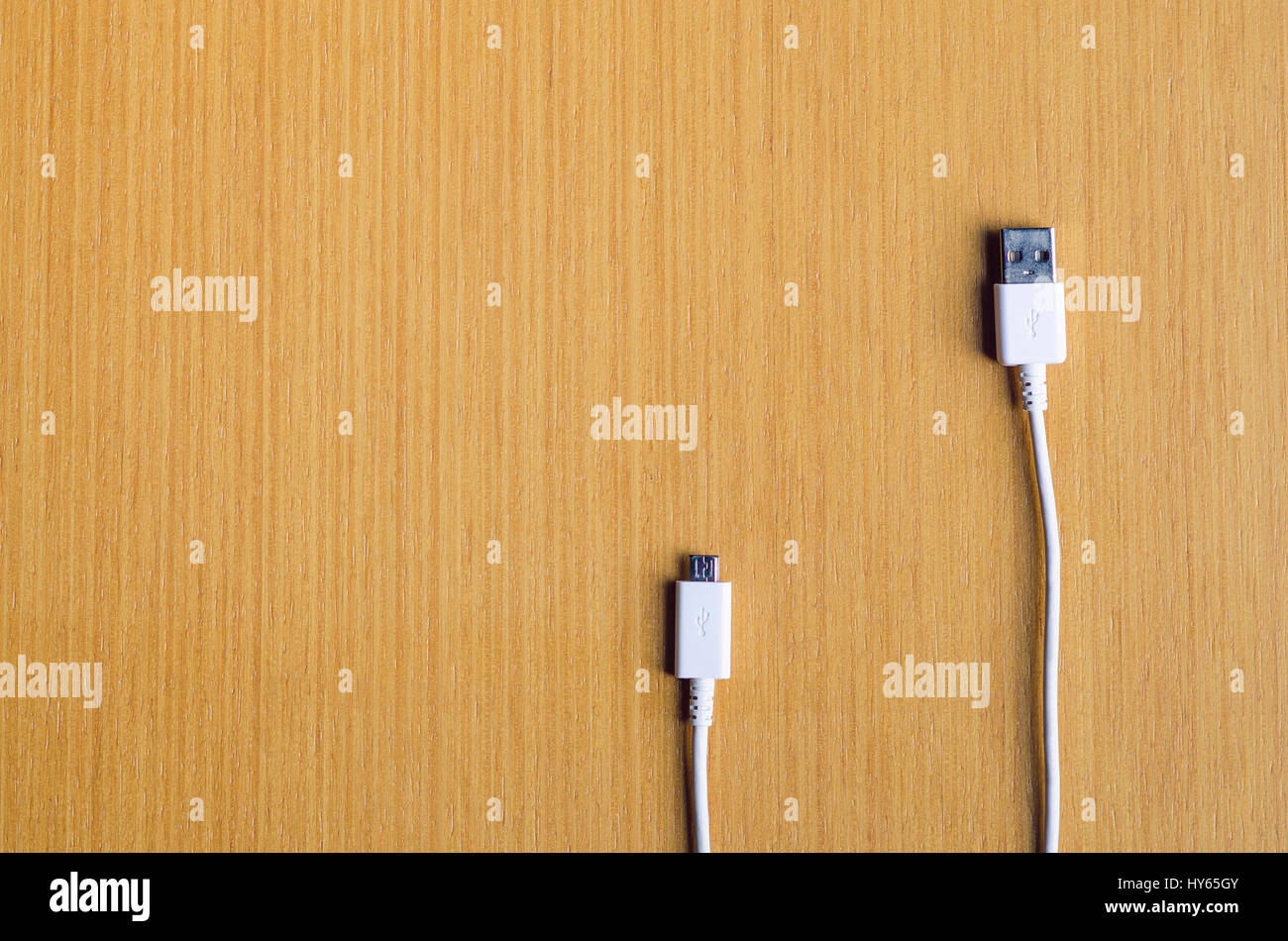 White USB cable with standard and micro port on the wooden background ...