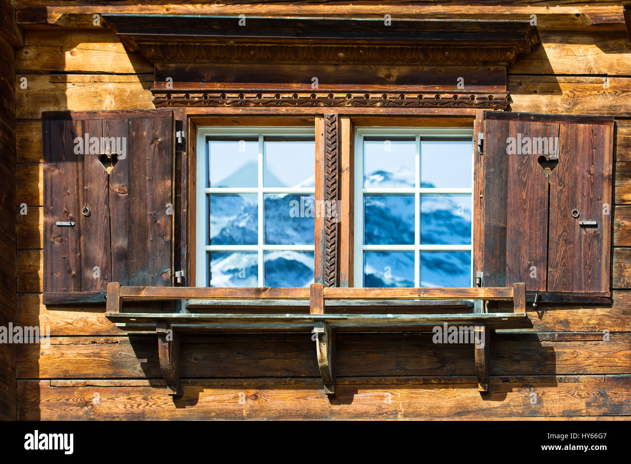 Typical wooden house window in Swiss Mountains mirrored in the Engadine ...